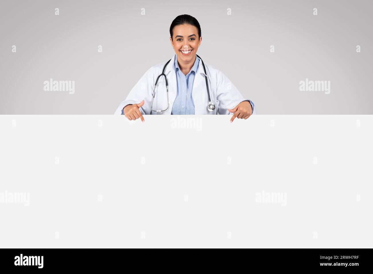Free checkup. Happy young latin doctor woman in medical uniform showing ...