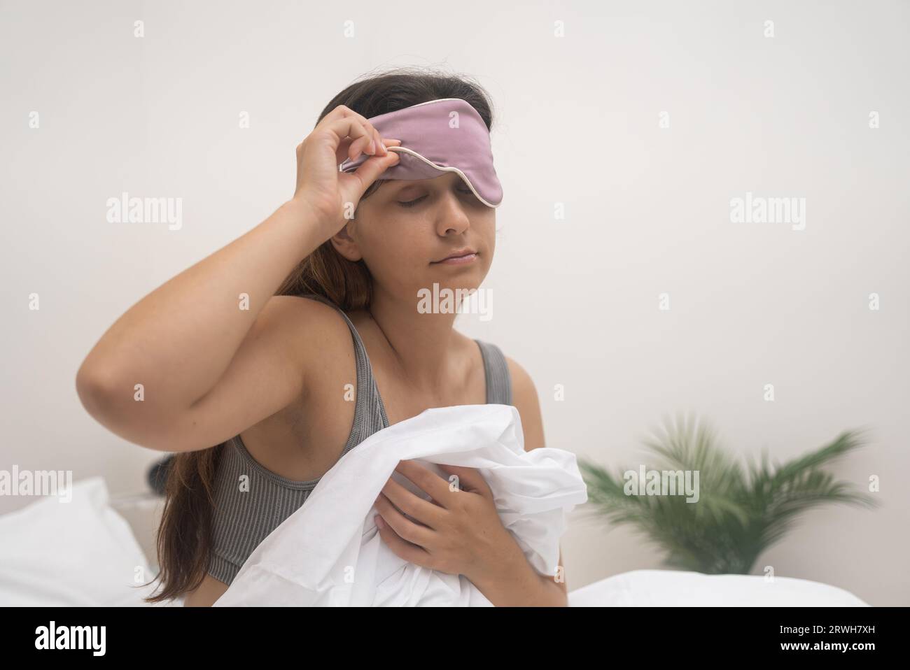Tired woman with closed eyes lifts sleeping mask unhappy with morning ...
