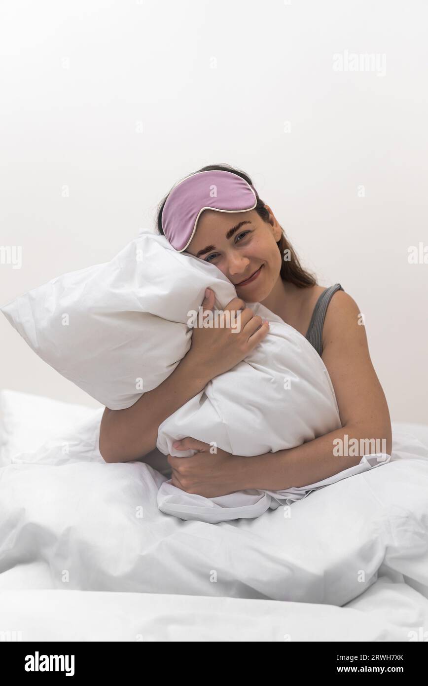 beautiful lady, wearing sleep mask, smiles, clutching white pillow on ...