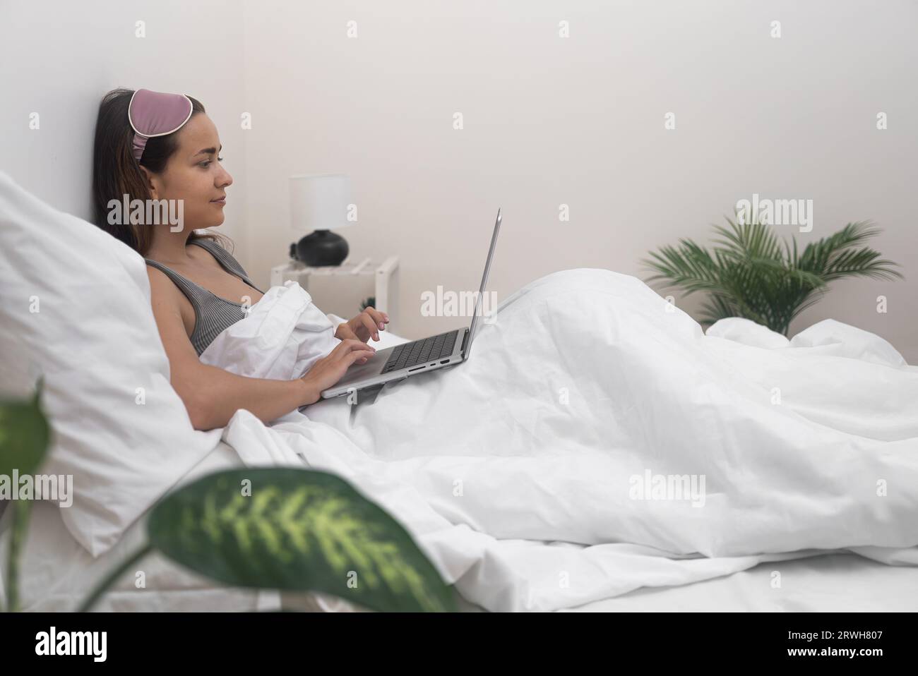 woman in blanket, multitasks by working online and studying remotely ...