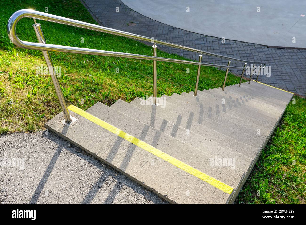 Outdoor concrete stairs with polished steel railing, view down, yellow ...