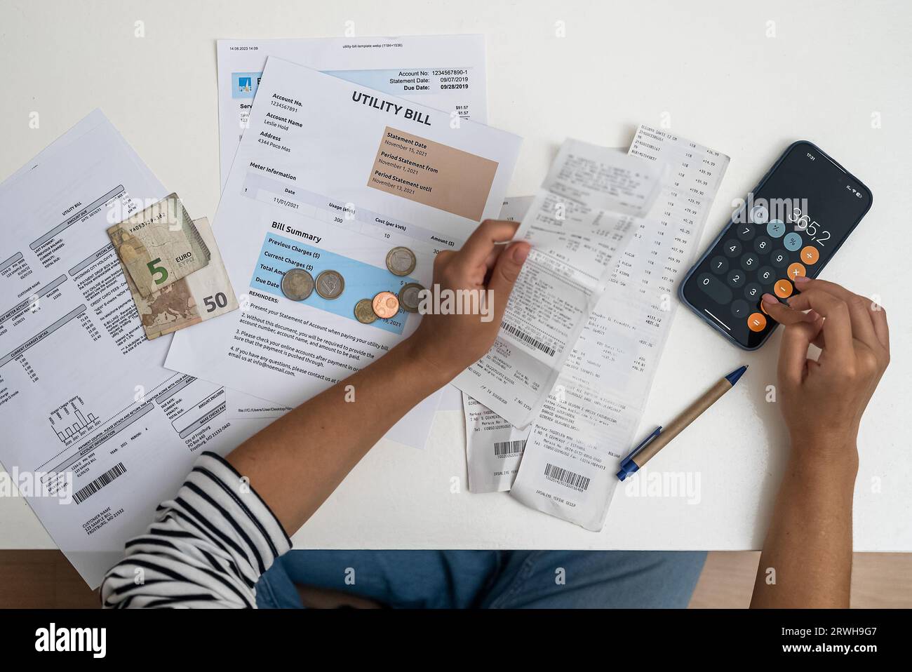 woman counts utility bank bills on floor, employing smartphone ...