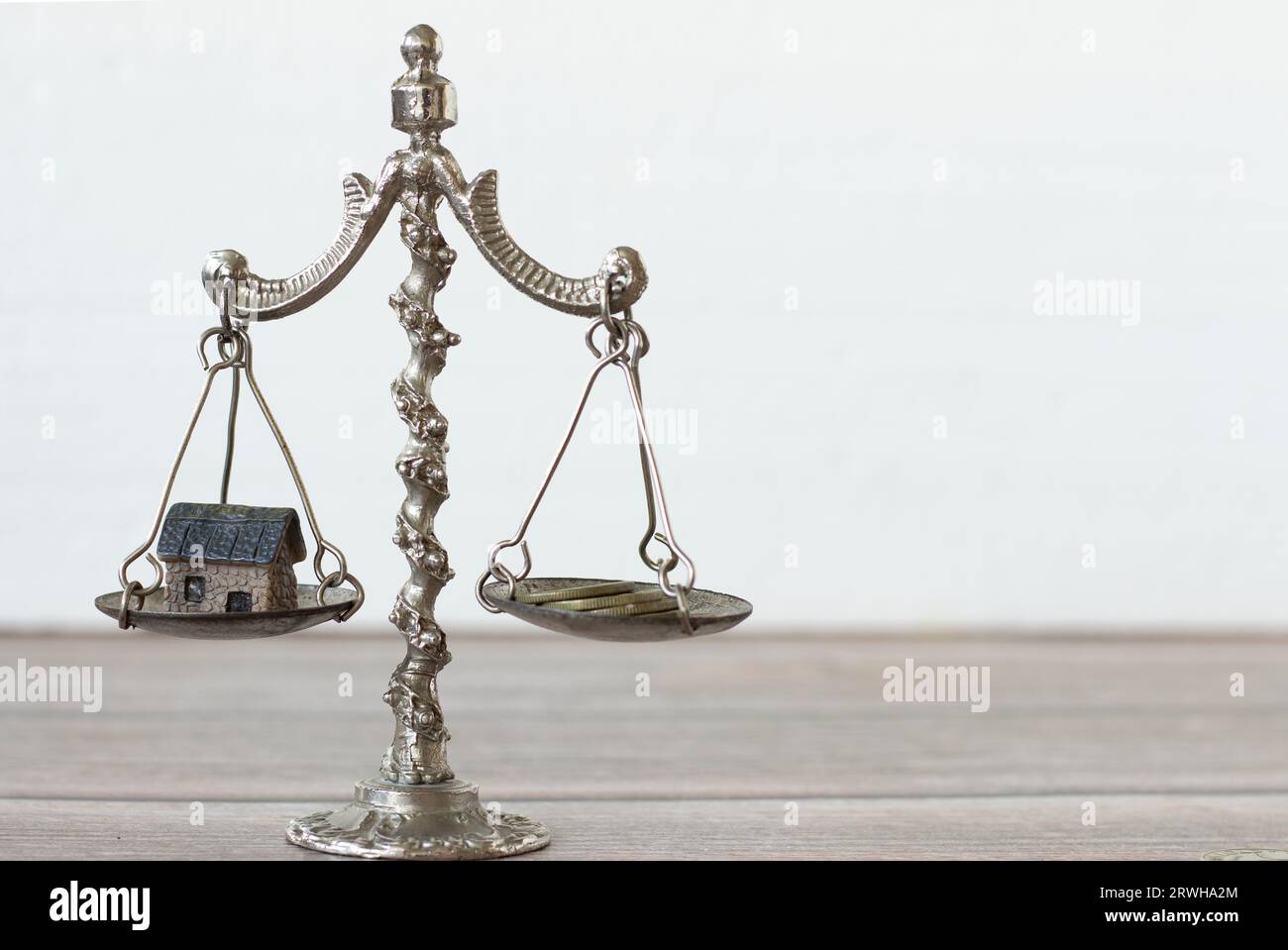 Vintage balance scales with small house on one side and few golden ...