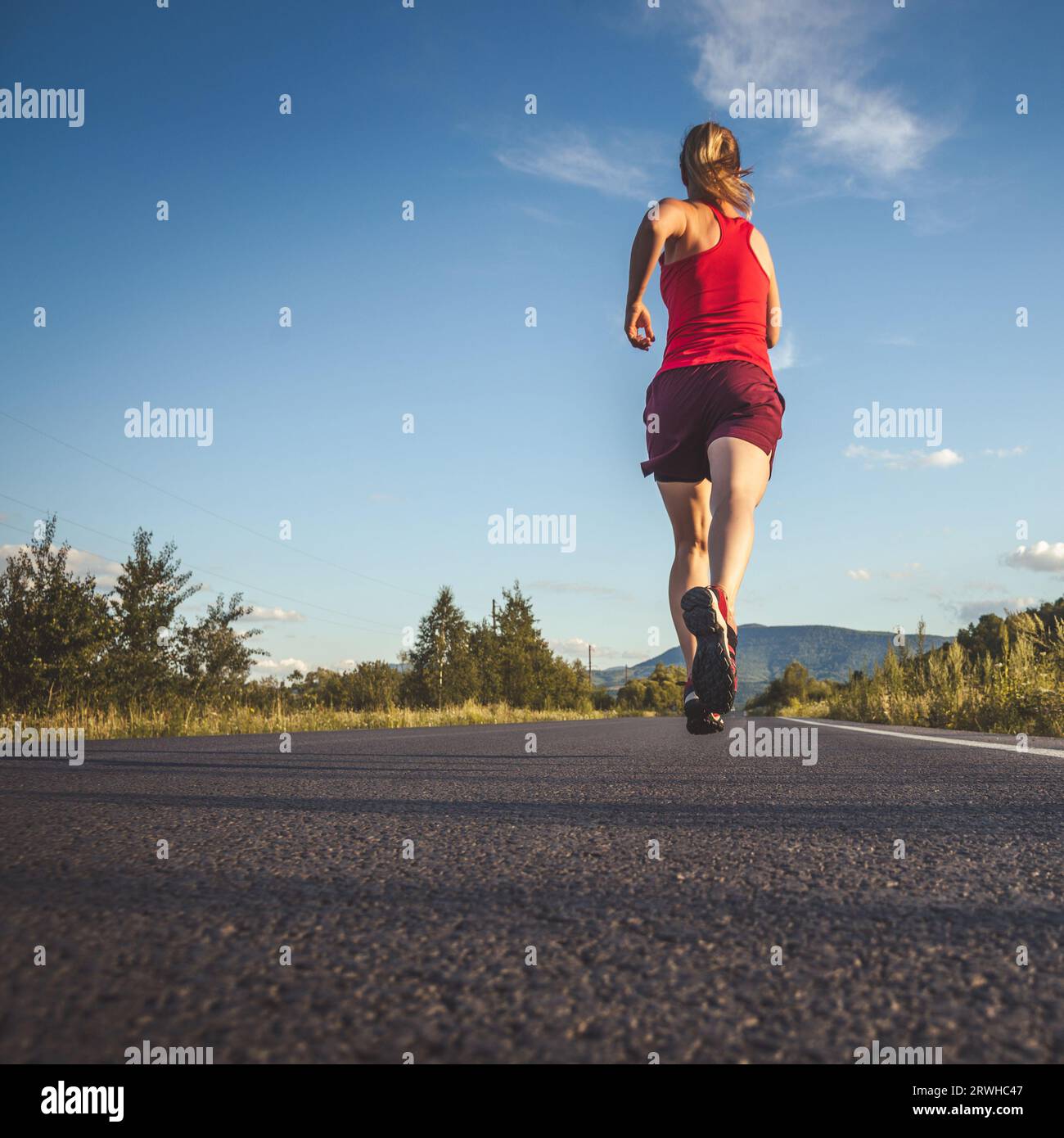 Fitness blonde woman running on the asphalt road at the mountains Stock ...