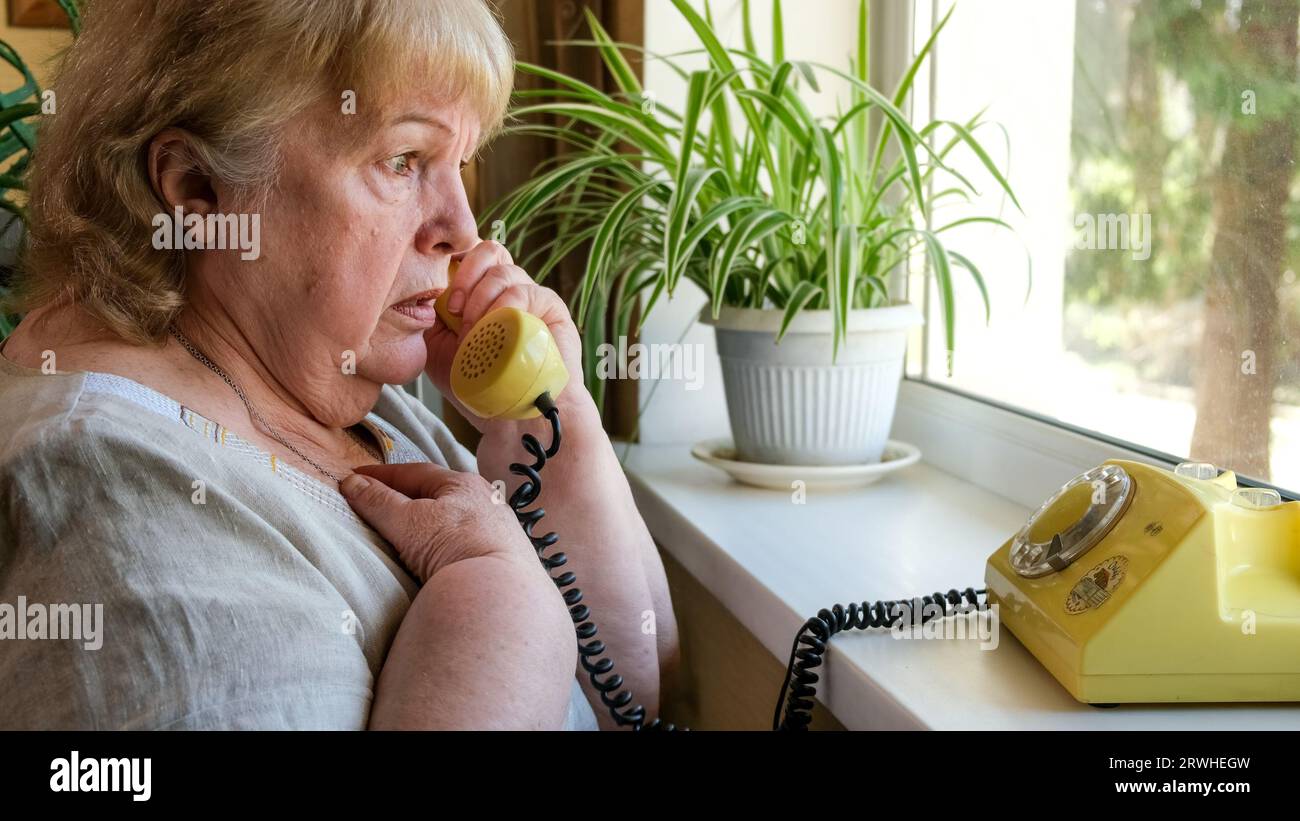 Old woman receives phone call from a scammer. Frightened grandmother ...