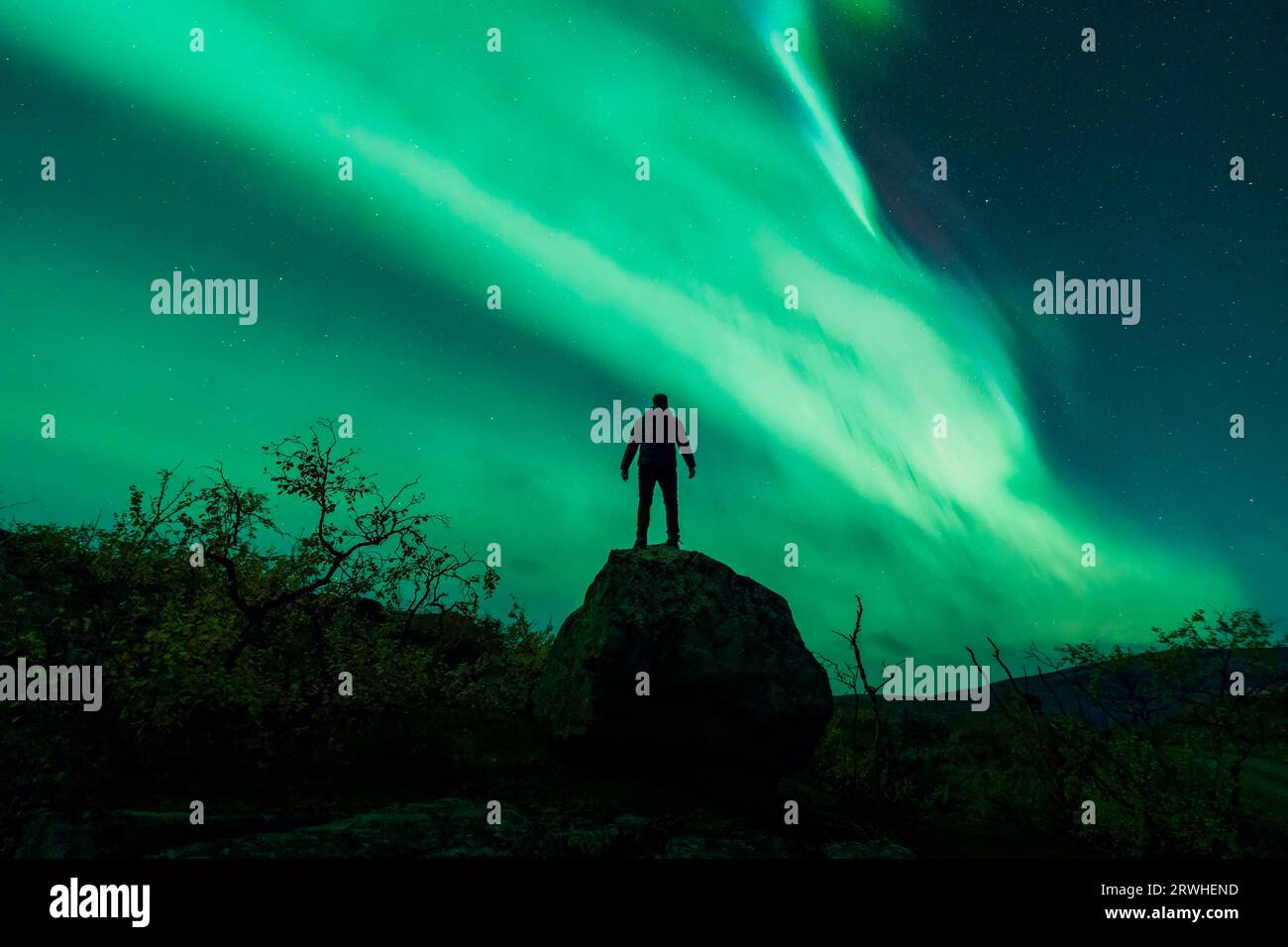 A silhouette of young adventurous male traveller watching the northern ...