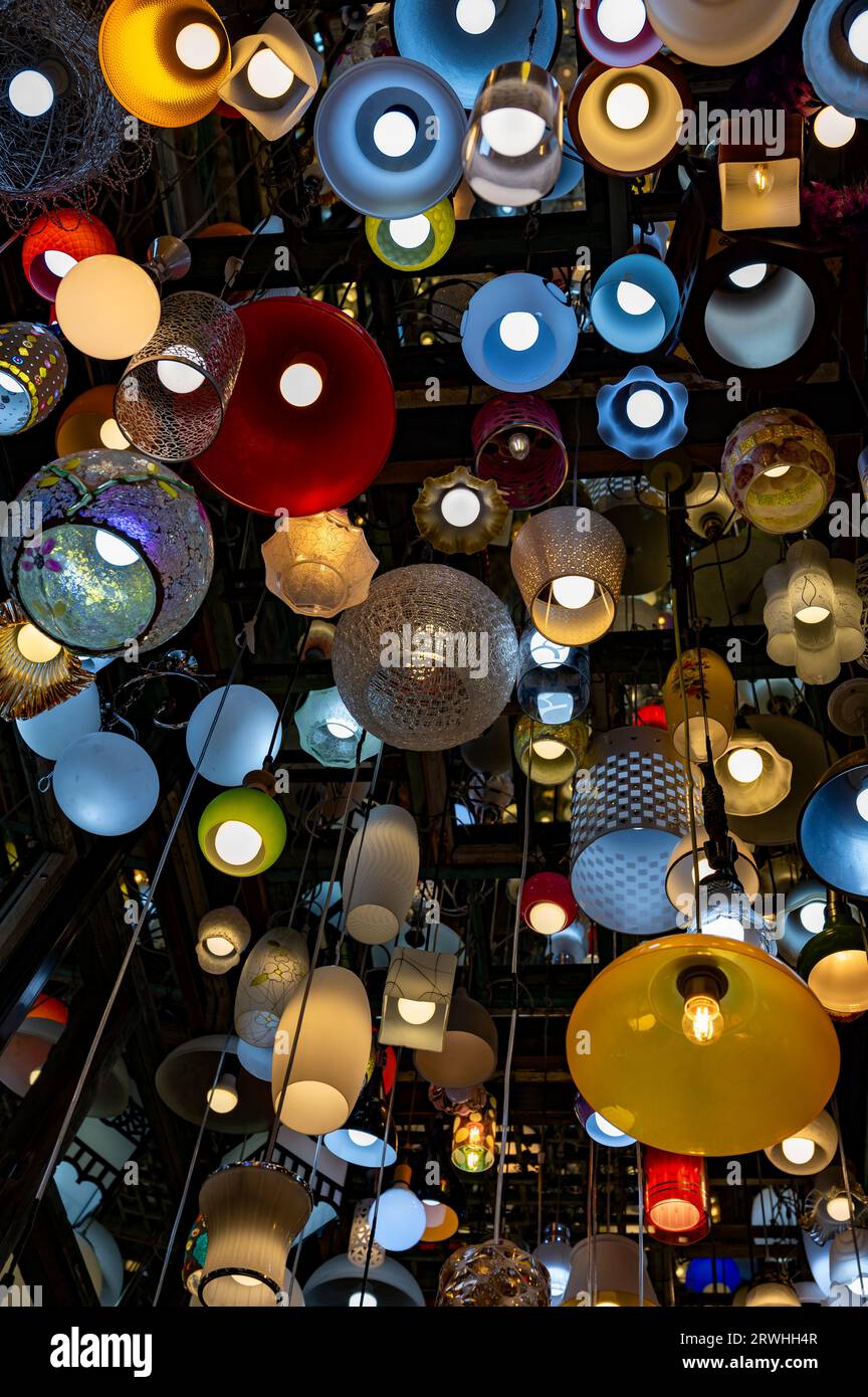 Many different ceiling lamps with lightbulbs in dark room with wall ...