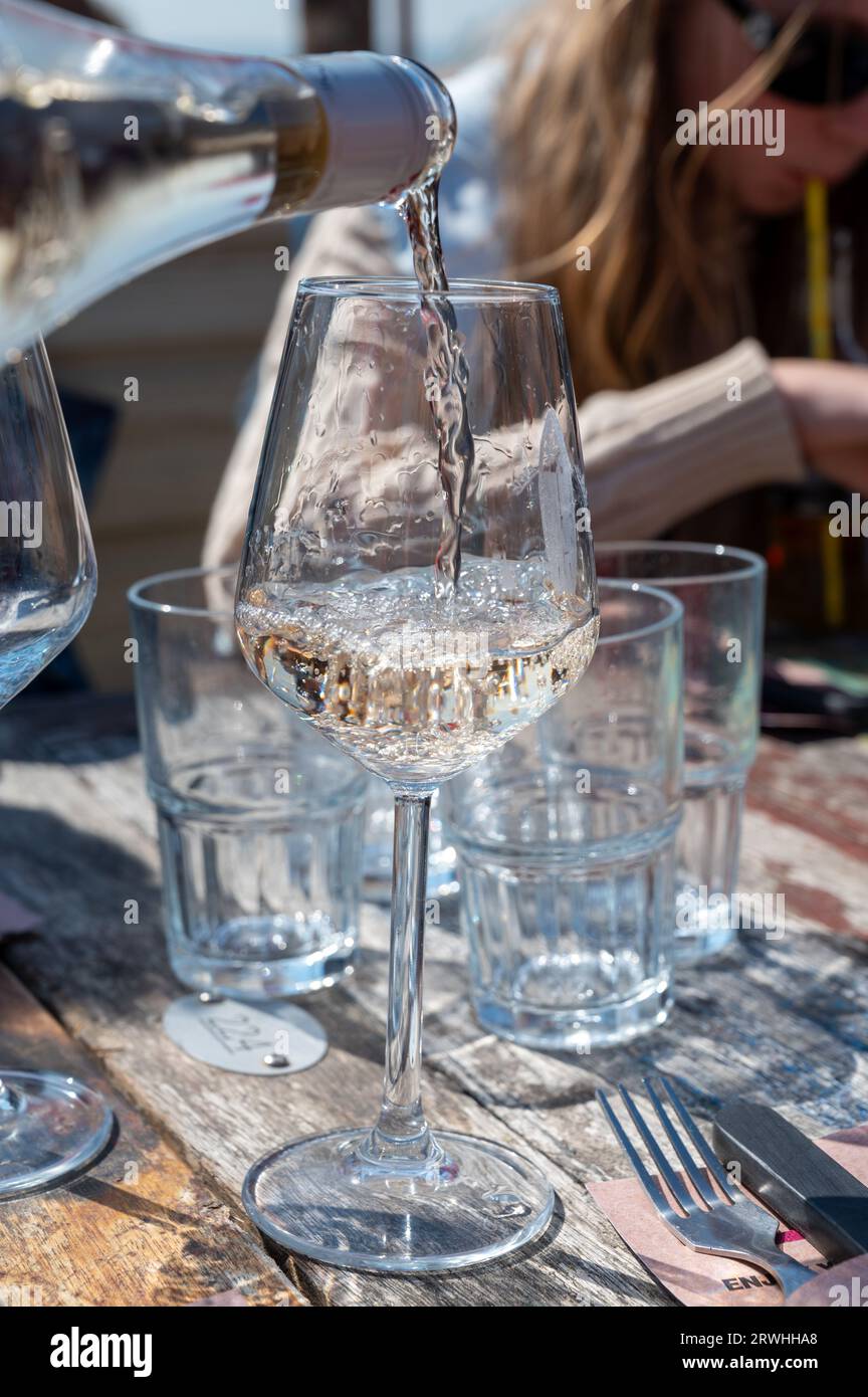 Drinking of pinot grigio dry cold wine, served outdoor in beach cafe in ...