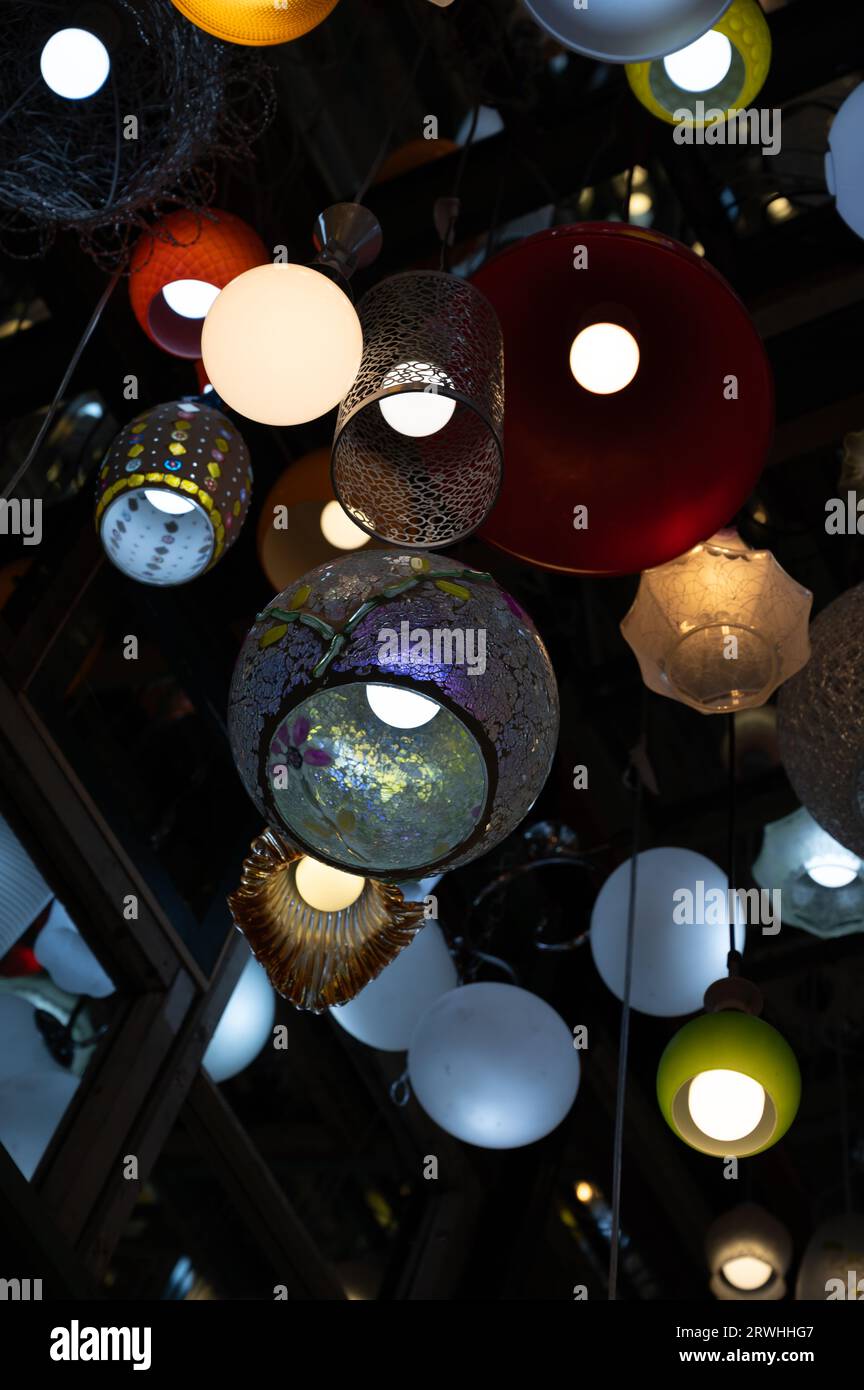 Many different ceiling lamps with lightbulbs in dark room with wall ...