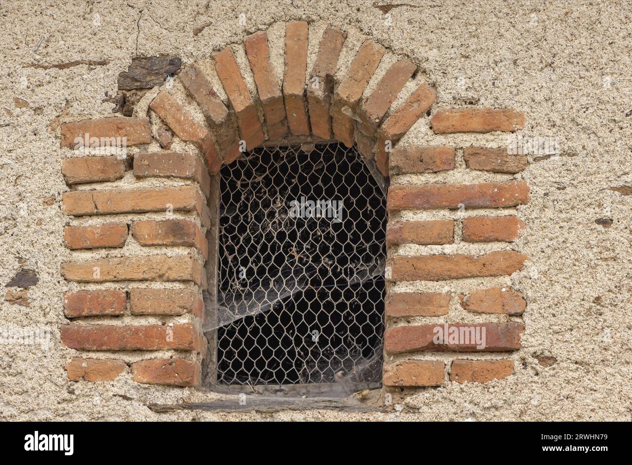 Arched red brick window with netting and cobwebs Stock Photo - Alamy