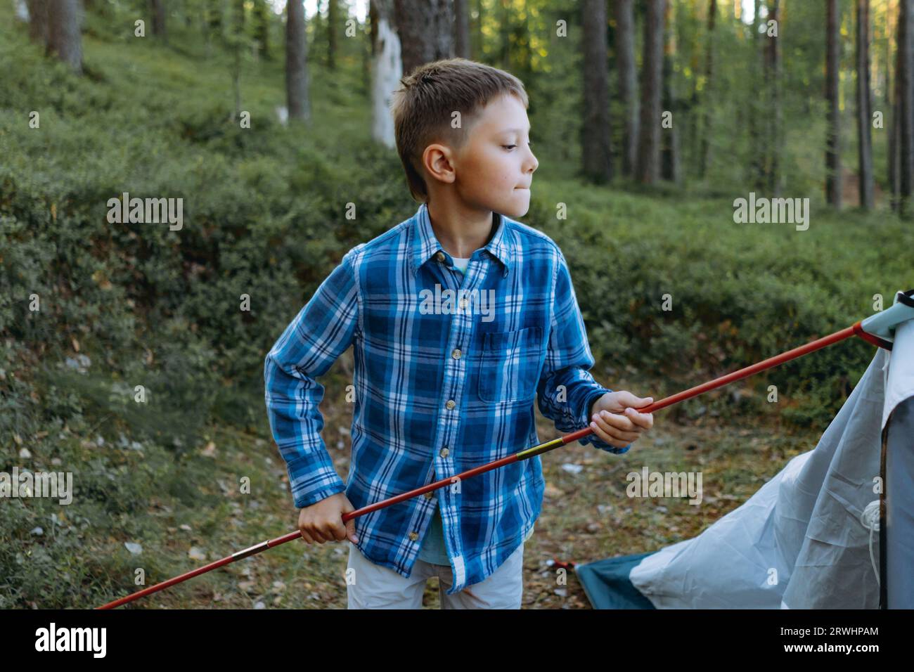 cute caucasian boy putting up a tent holding a tent poles. Family camping concept Stock Photo ...