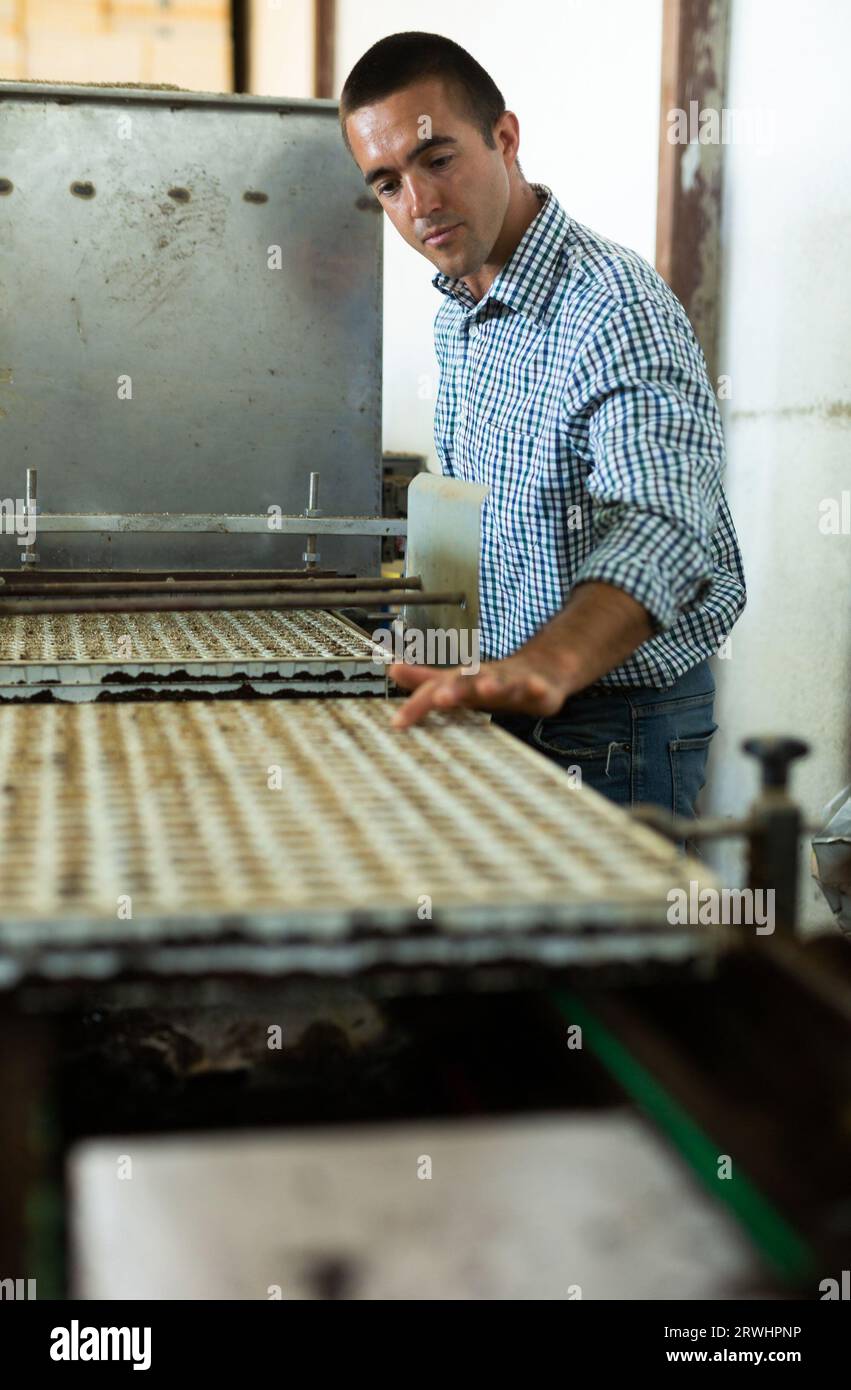 Farmer man working with automatic filling and seeding line for growing ...