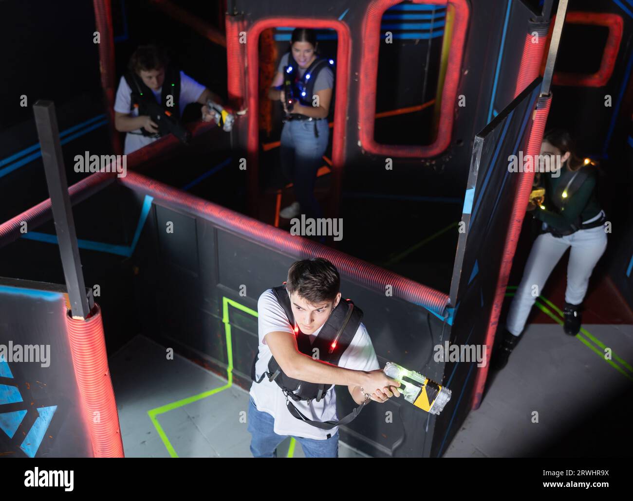 Laser tag players positive smiling guys and girls playing in teams in ...