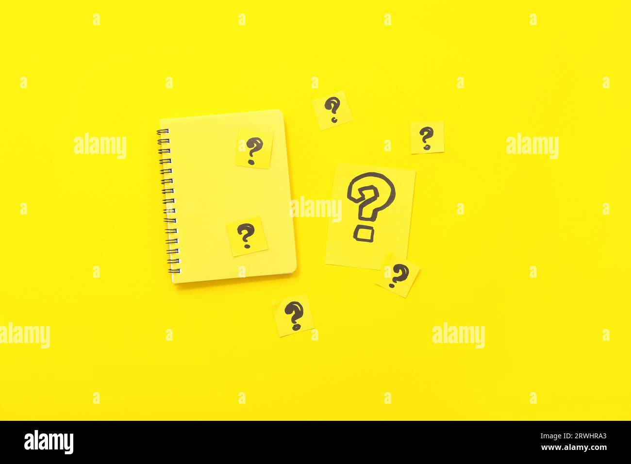 Notebook with paper question marks on yellow background Stock Photo - Alamy