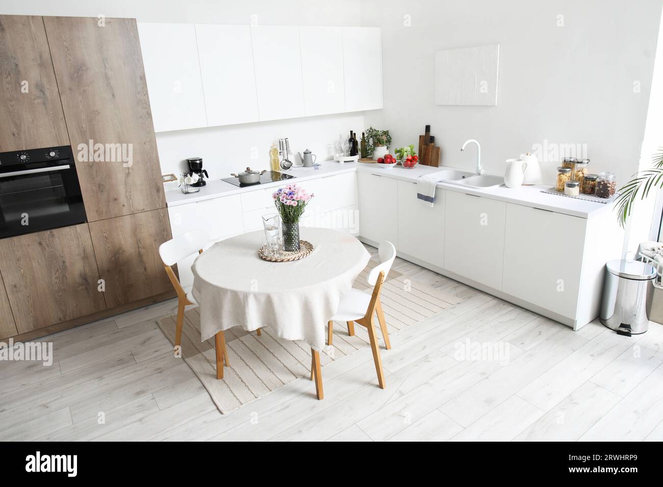 Interior of modern kitchen with flowers on dining table Stock Photo - Alamy