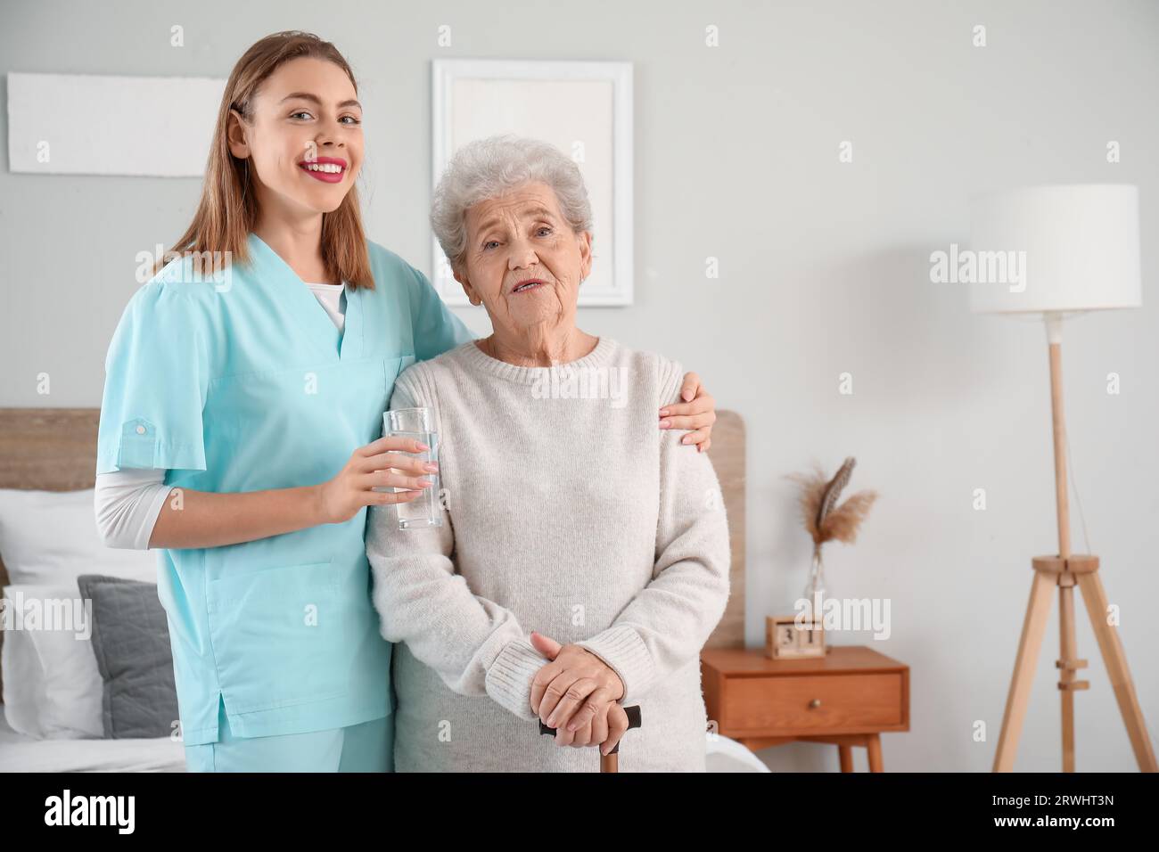 Female caregiver with senior woman in bedroom Stock Photo - Alamy