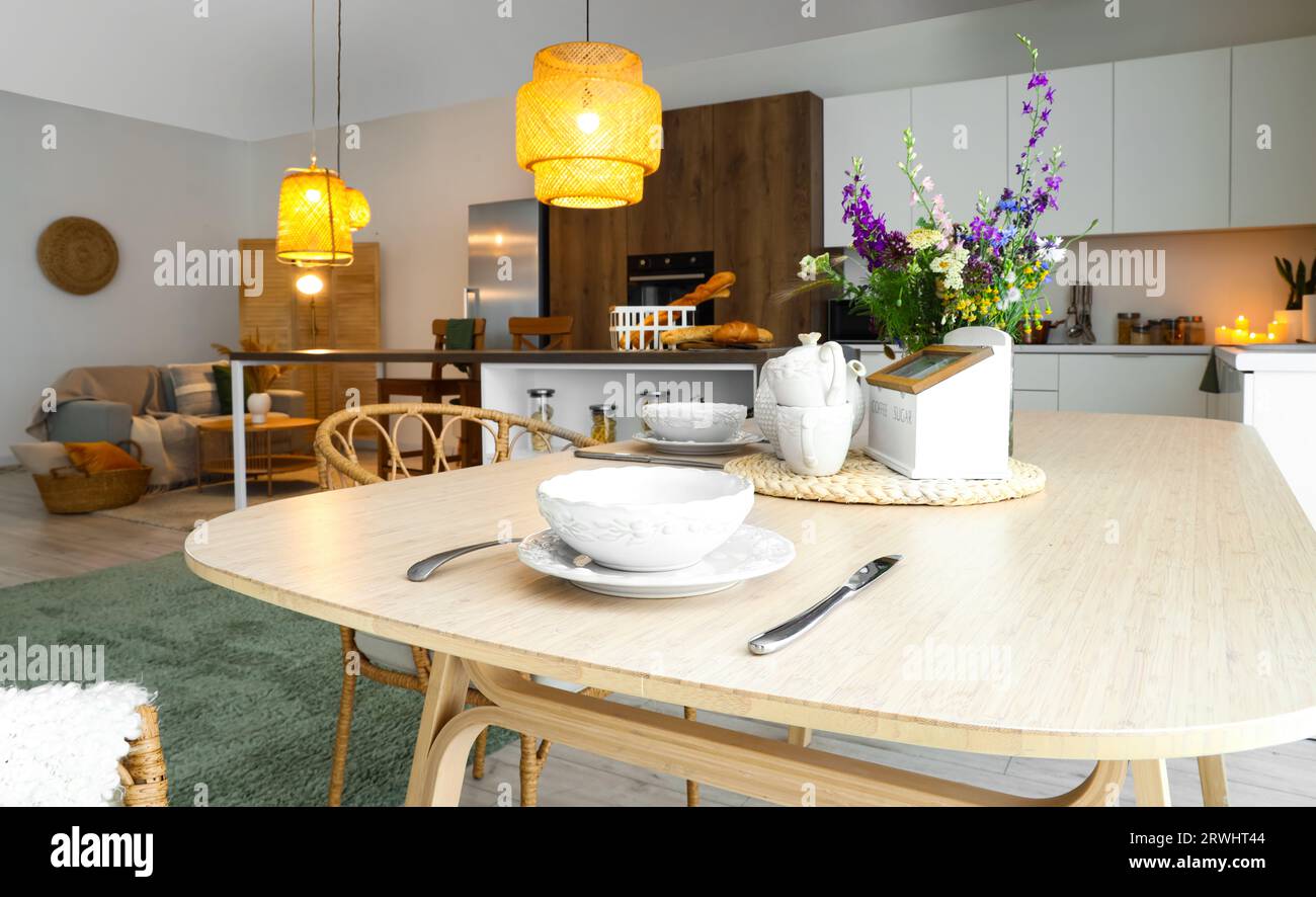 Dining table served with bowls and cutlery in interior of modern ...