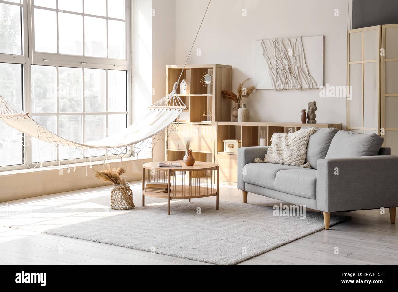 Interior of light living room with hammock, table and sofa Stock Photo ...