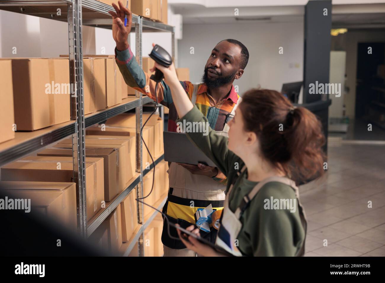 Storehouse supervisor showing colleague invoice code on device to find ...