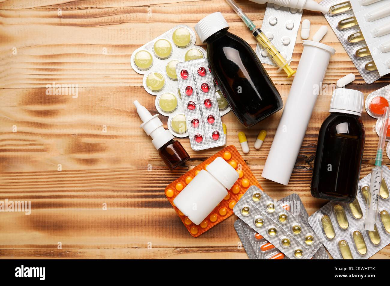 Different pills, syringes and bottles of medicines on wooden background ...