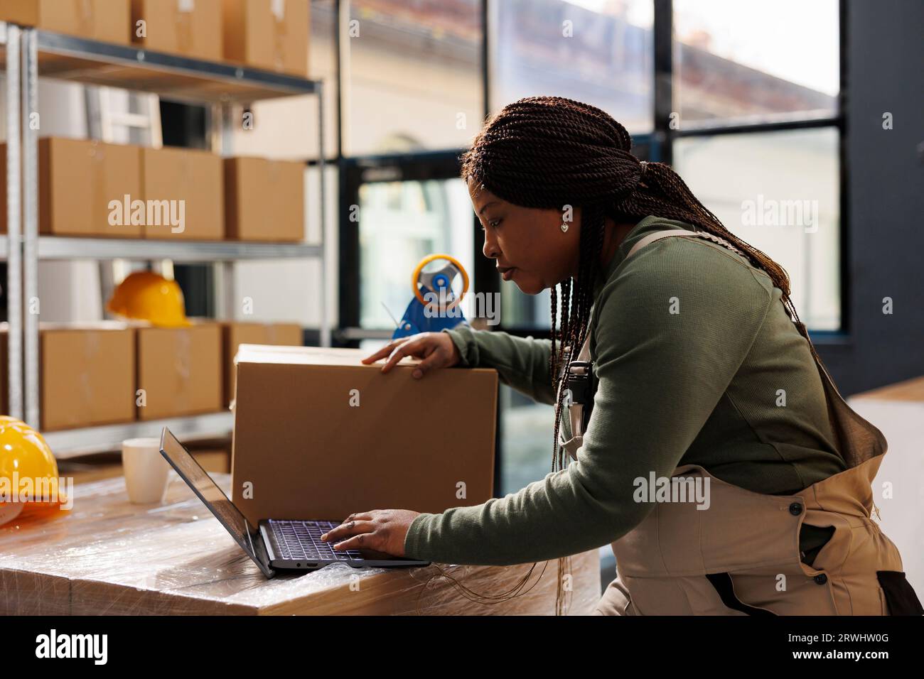 Stockroom employee checking customers orders on laptop, preparing ...