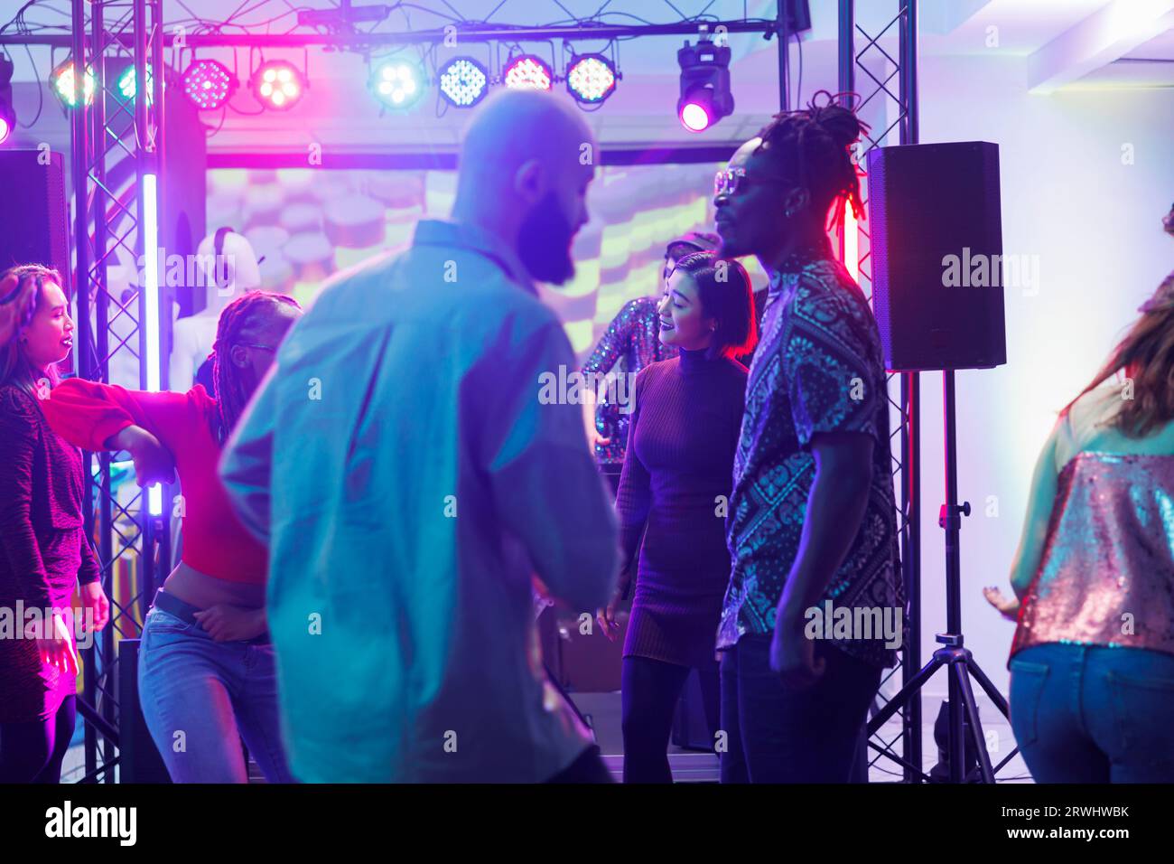 People partying on crowded dancefloor in dark nightclub illuminated ...