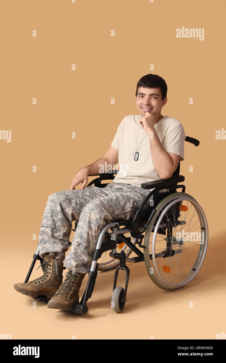 Young soldier in wheelchair on beige background Stock Photo - Alamy