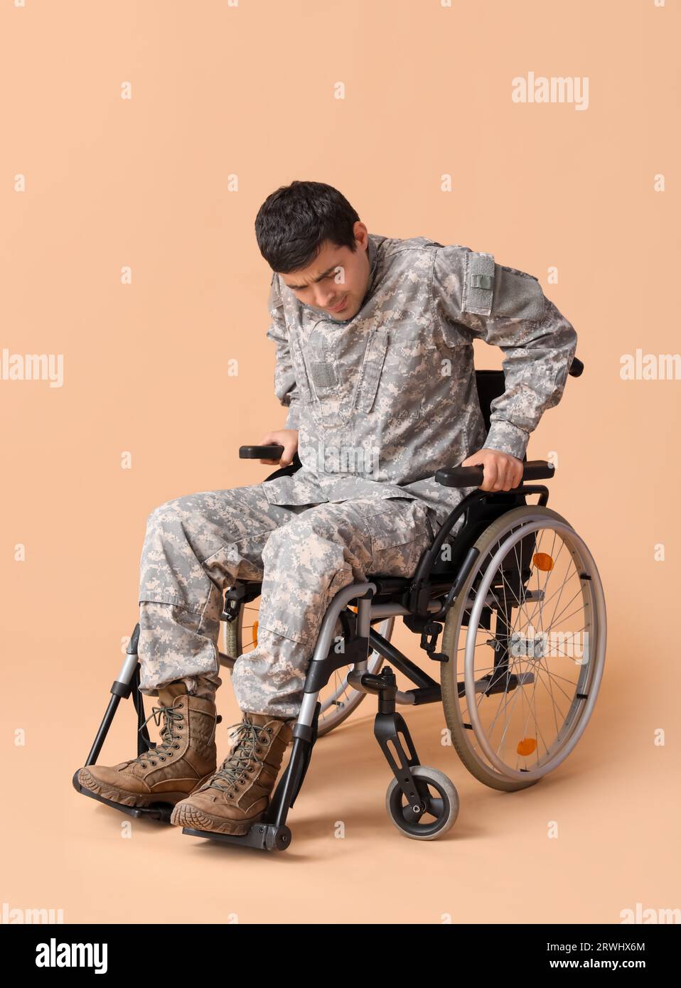 Young soldier in wheelchair on beige background Stock Photo - Alamy