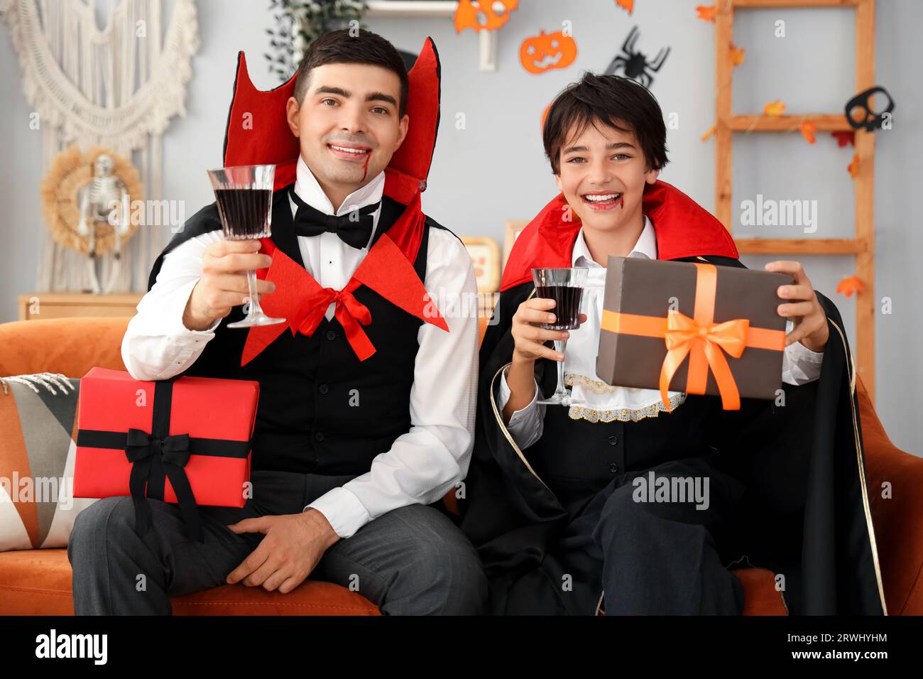 Little boy and his father dressed for Halloween as vampires with gifts ...
