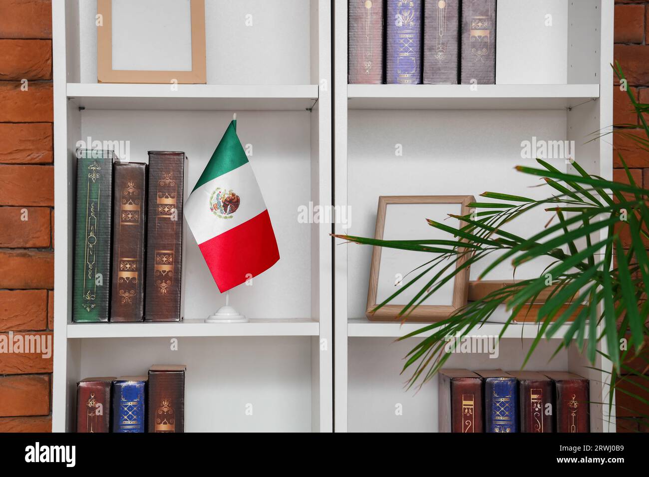 Bookcase with Mexican flag and frames near brick wall Stock Photo - Alamy