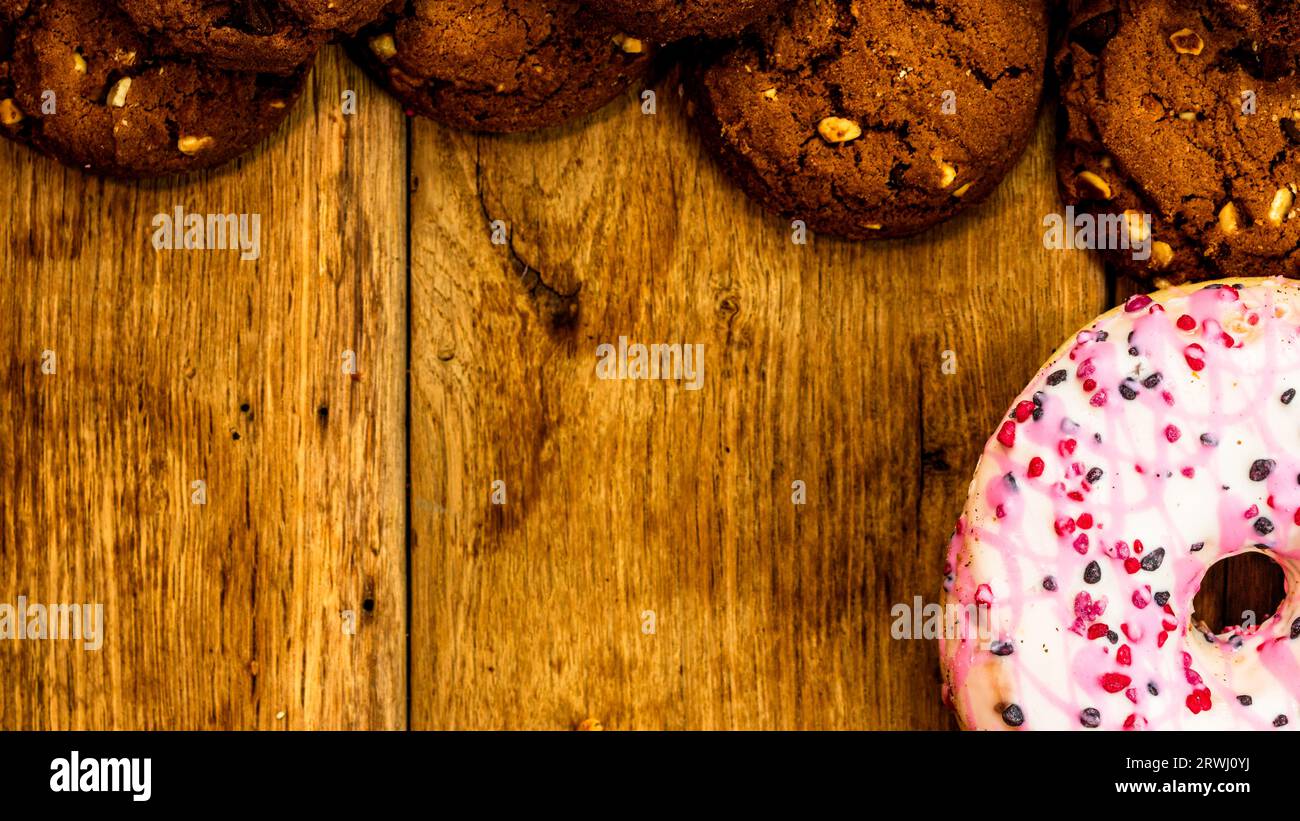 Frame made of chocolate chip cookies, biscuits and colorful donuts top ...