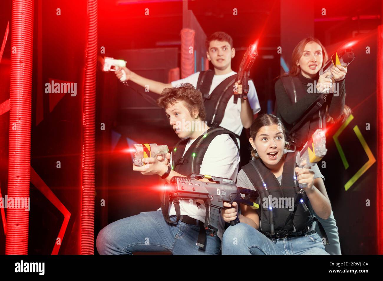 Four people with lasertag guns squatting in arena Stock Photo - Alamy
