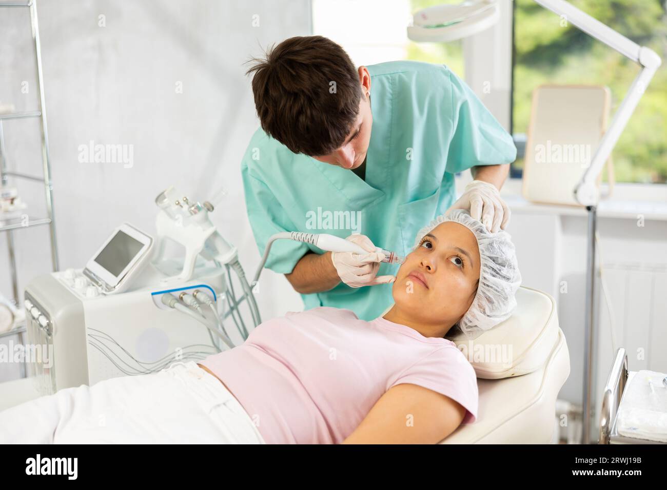 Young male cosmetologist doing cleansing procedure to young woman Stock ...