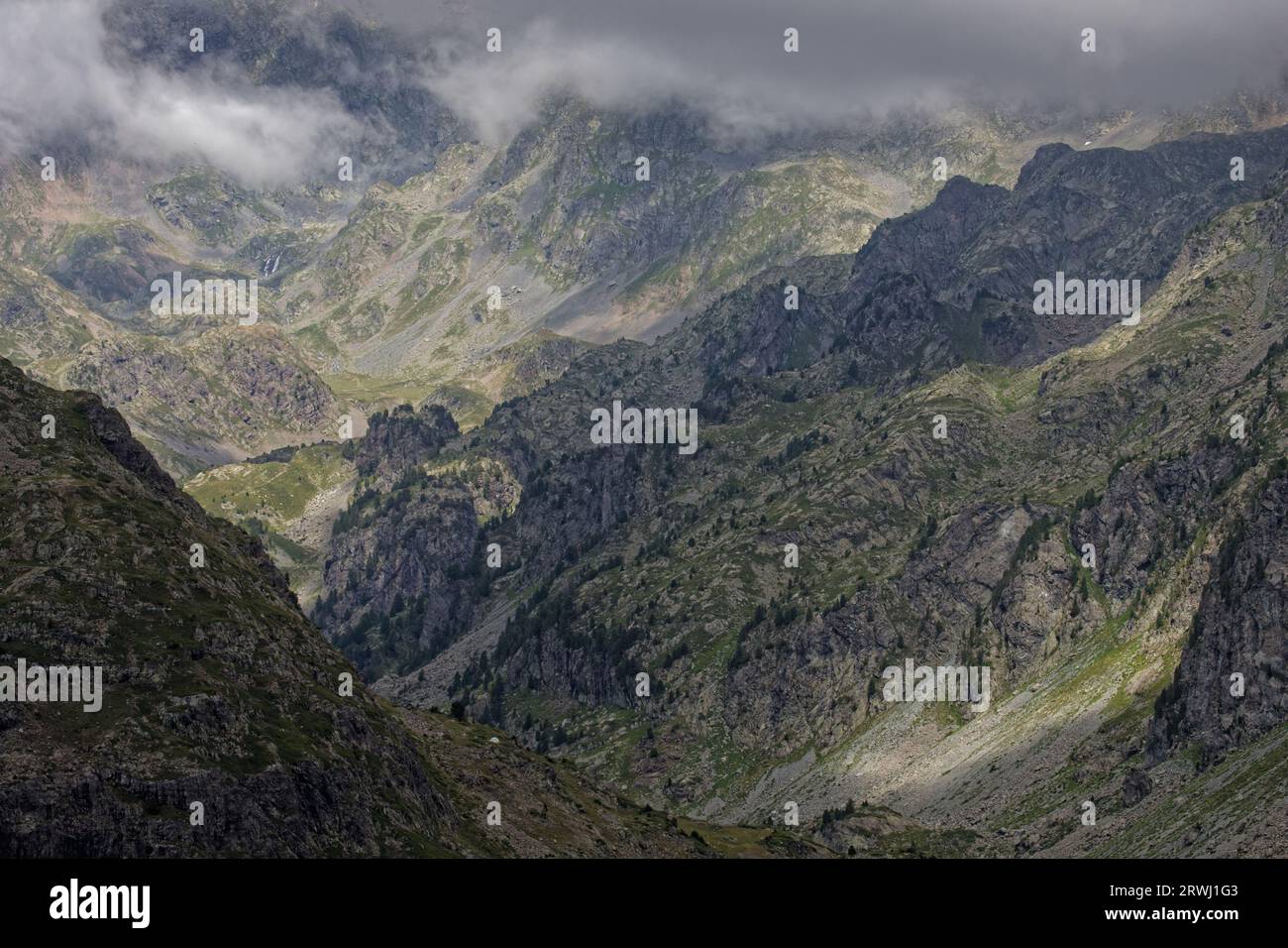 Clouds rise from the valley and surround the slopes and rocks Stock ...