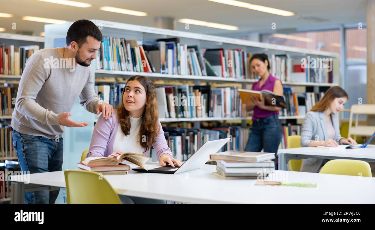 Male librarian helping focused adult student preparing to exam Stock ...