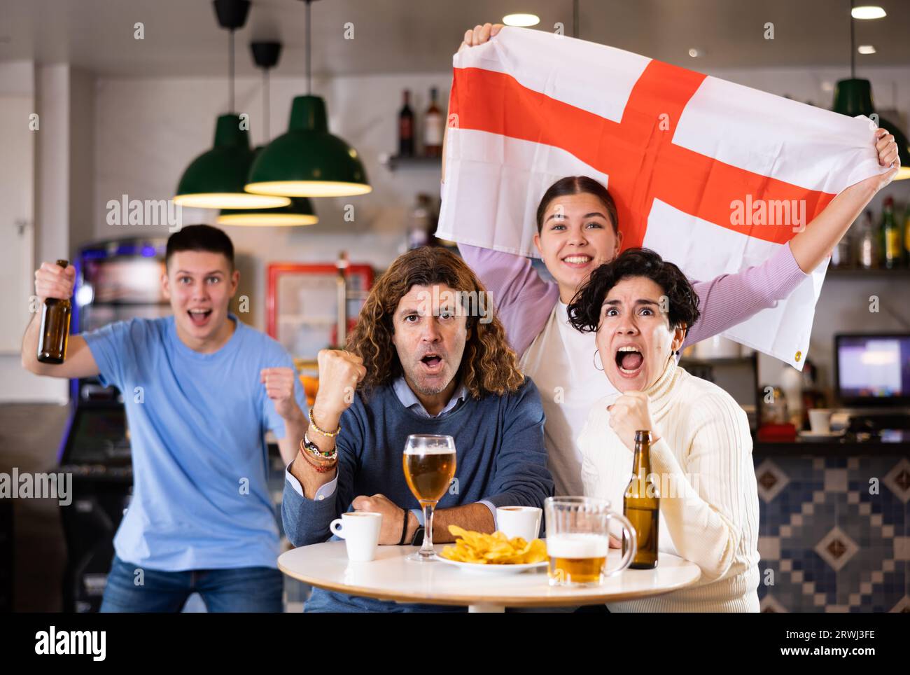 Enthusiastic company of young adult sports fans waving flag of England ...