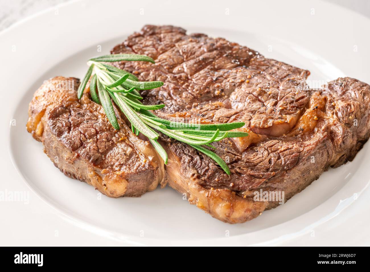 Whole rib eye steak with rosemary on the plate Stock Photo - Alamy