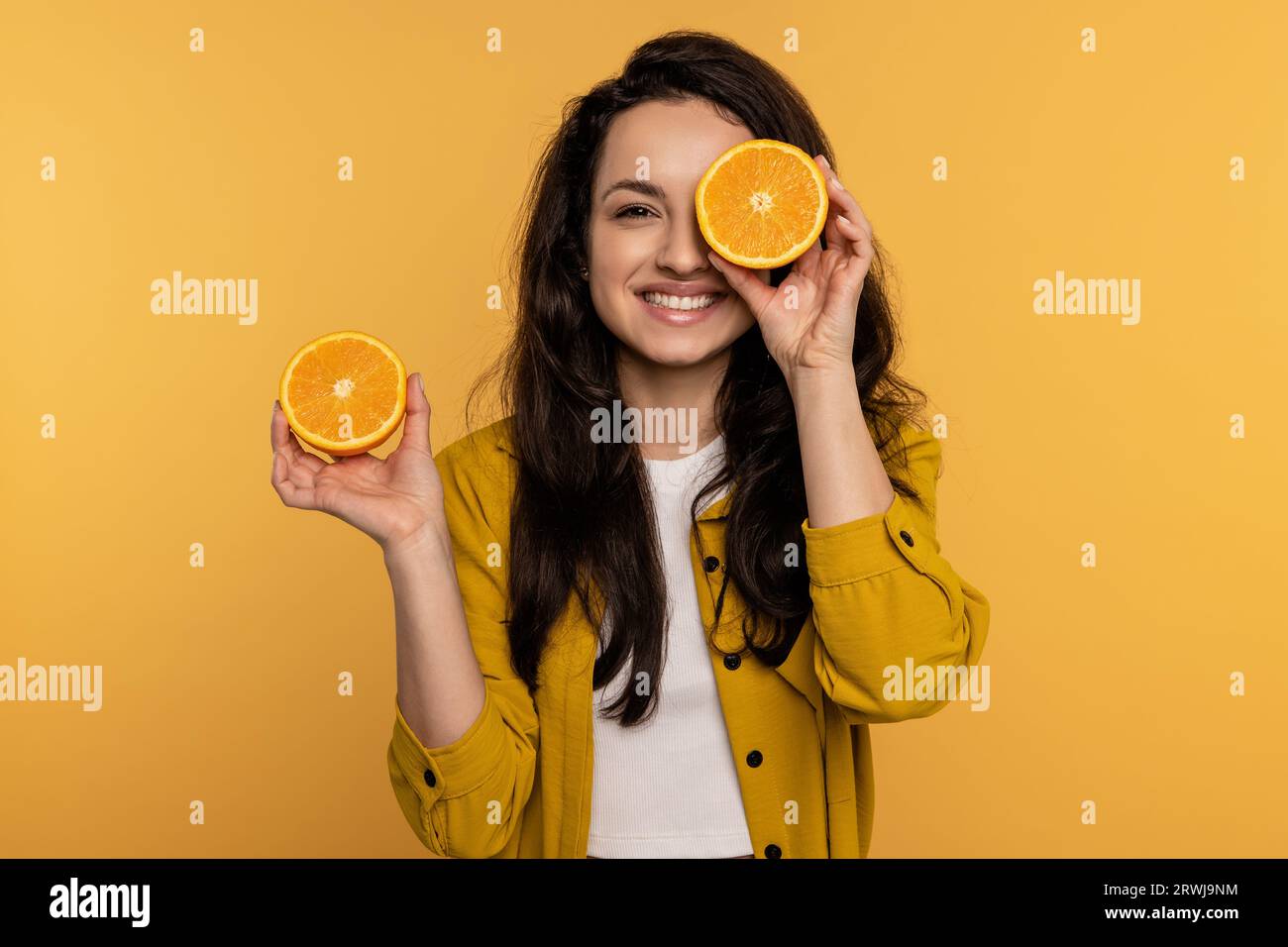 Merry young lady posing for the camera with citrus fruit halves against ...
