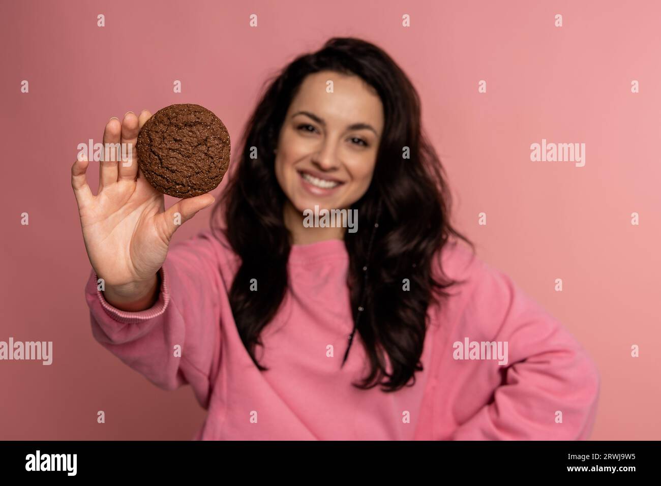 Pleased cute young woman showing her favorite oat biscuit during the ...