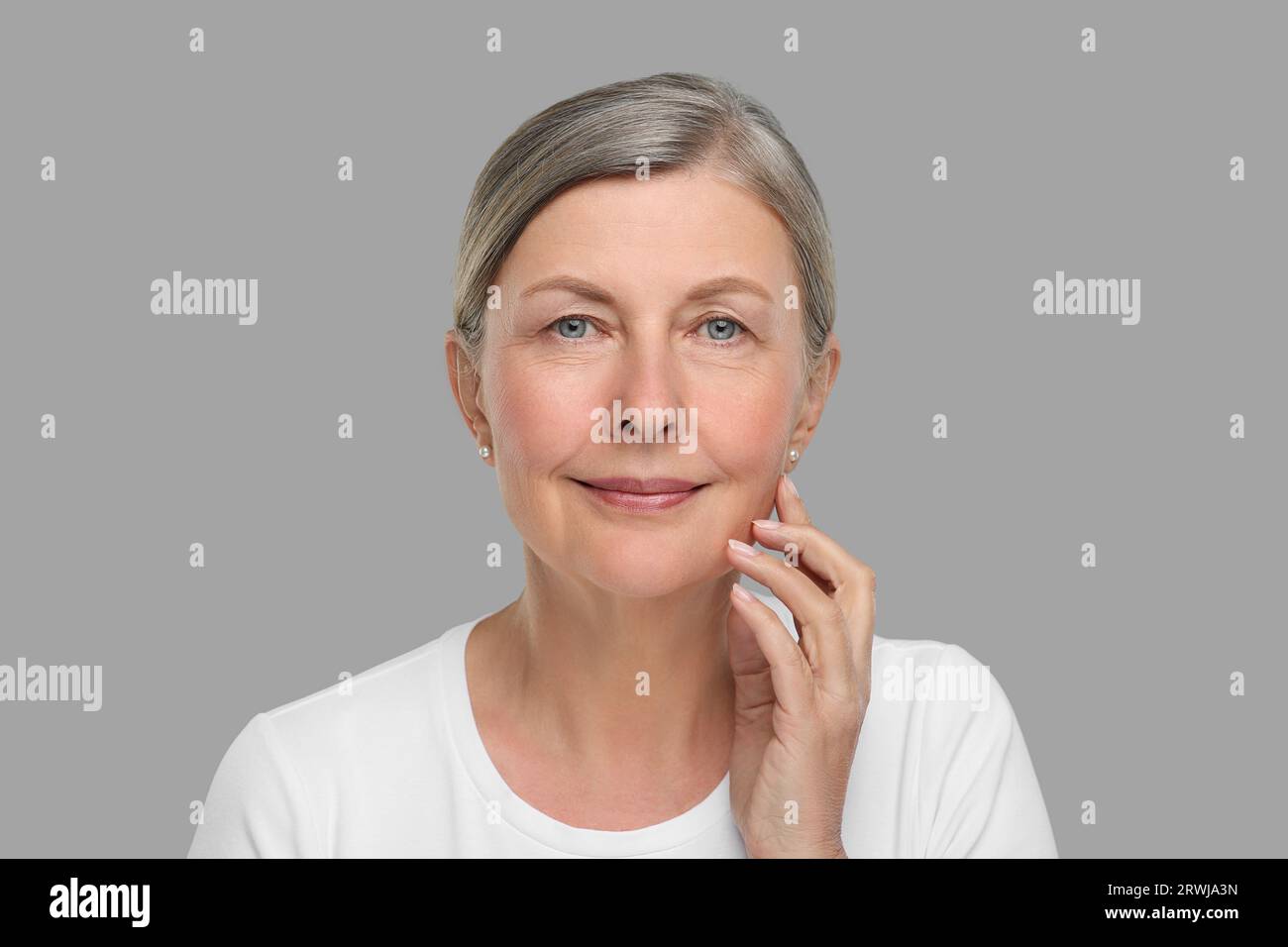 Portrait of senior woman with aging skin on grey background ...