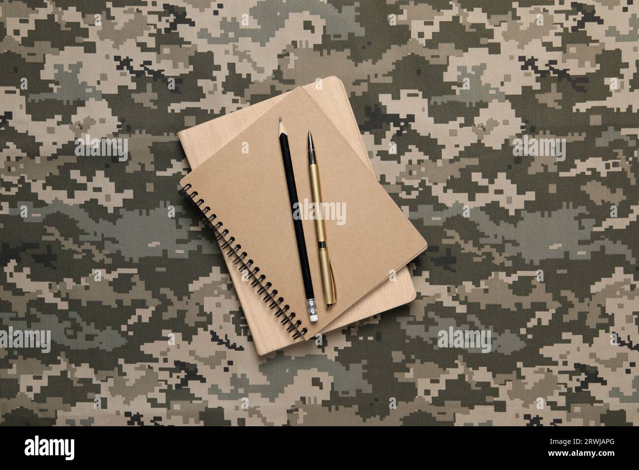 Notebooks, pen and pencil on camouflage background, top view. Military ...