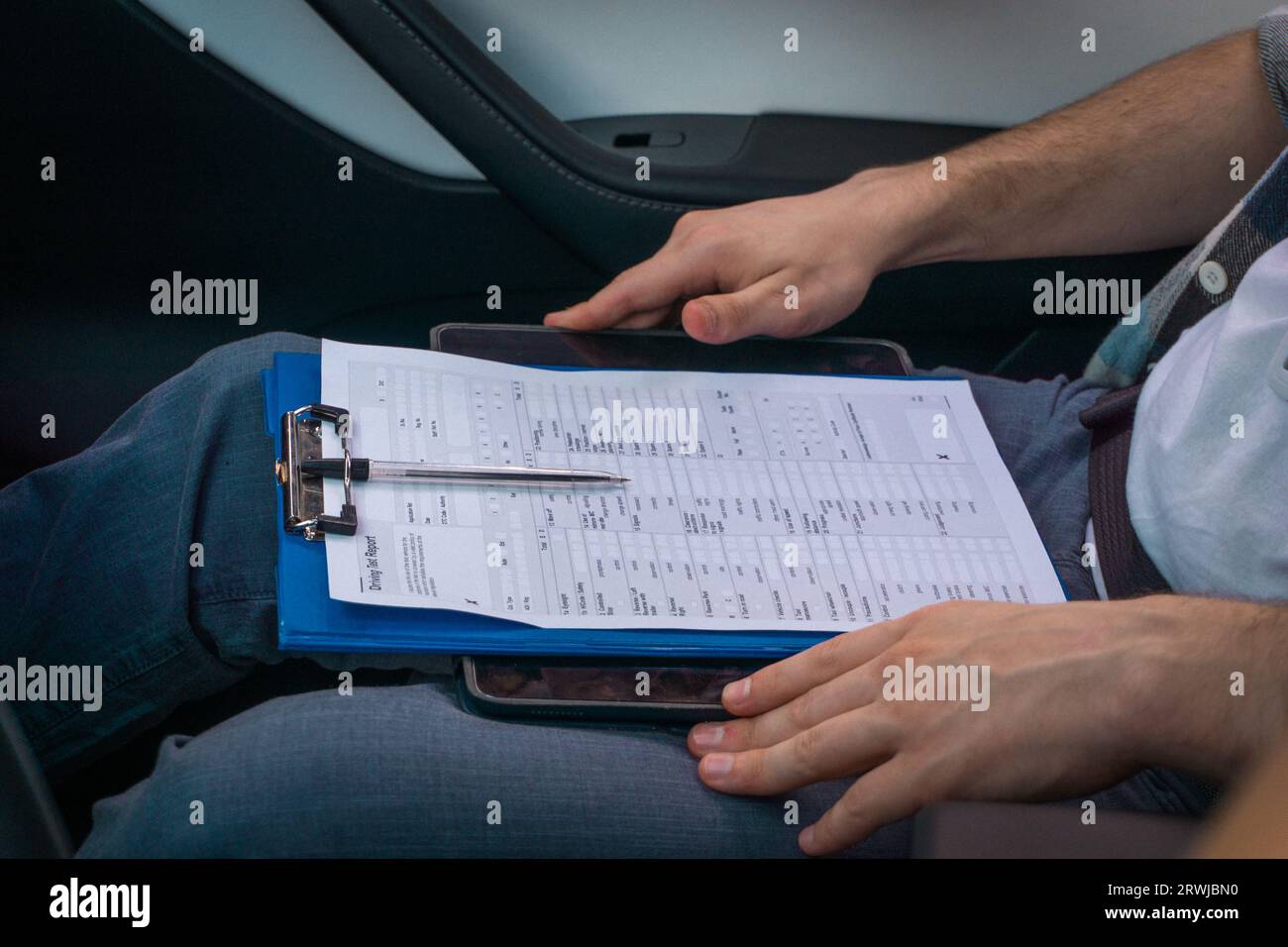 Male instructor sitting on the passenger seat with drive test report ...