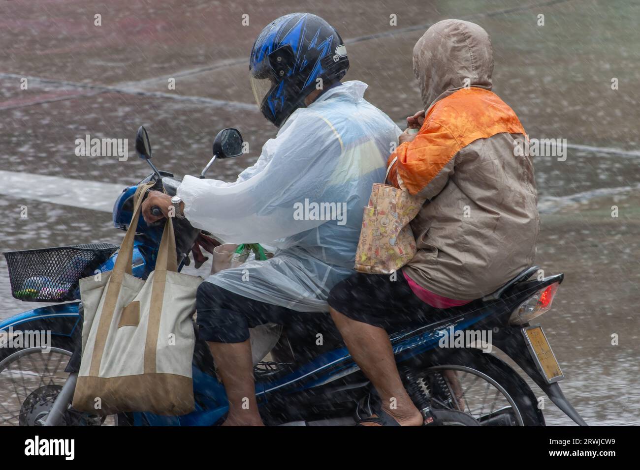 A moto-taxi drives with a passenger in the heavy rain, Bangkok ...