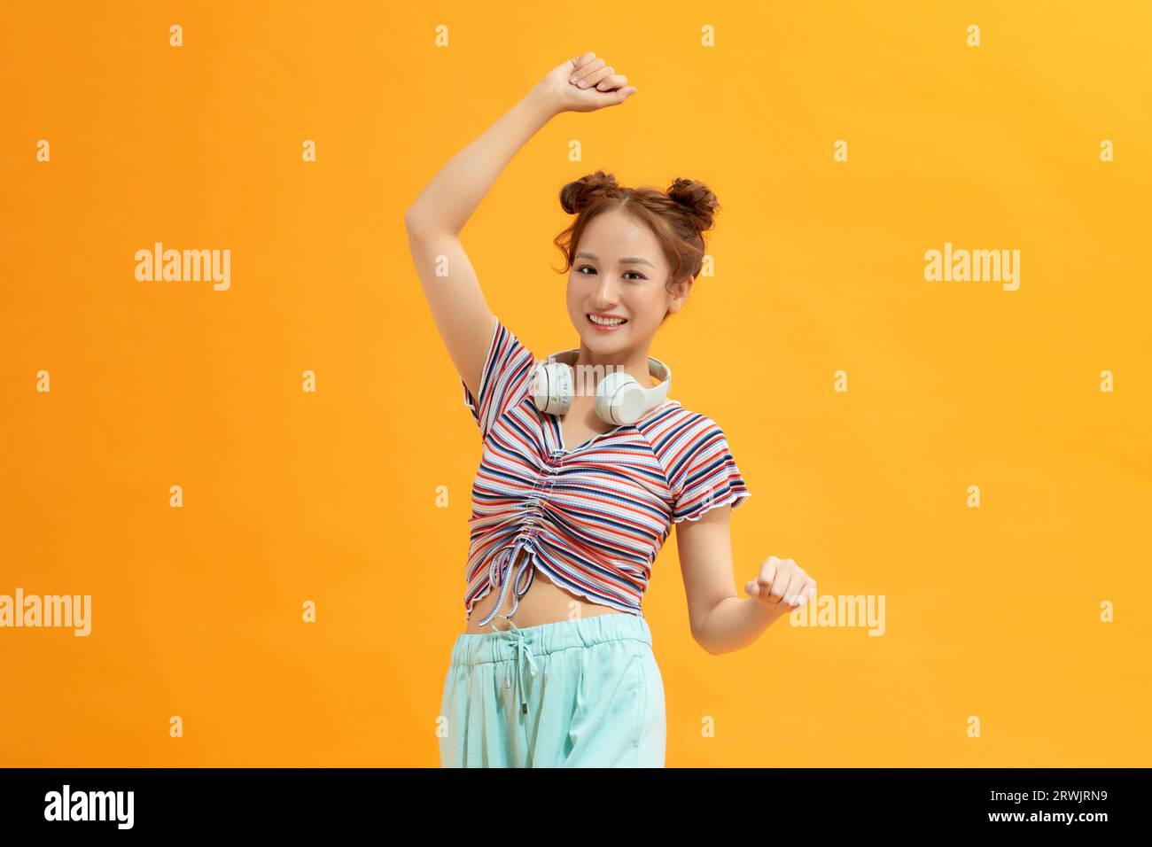 Portrait of a joyful lady with headphones on her neck dancing with a ...