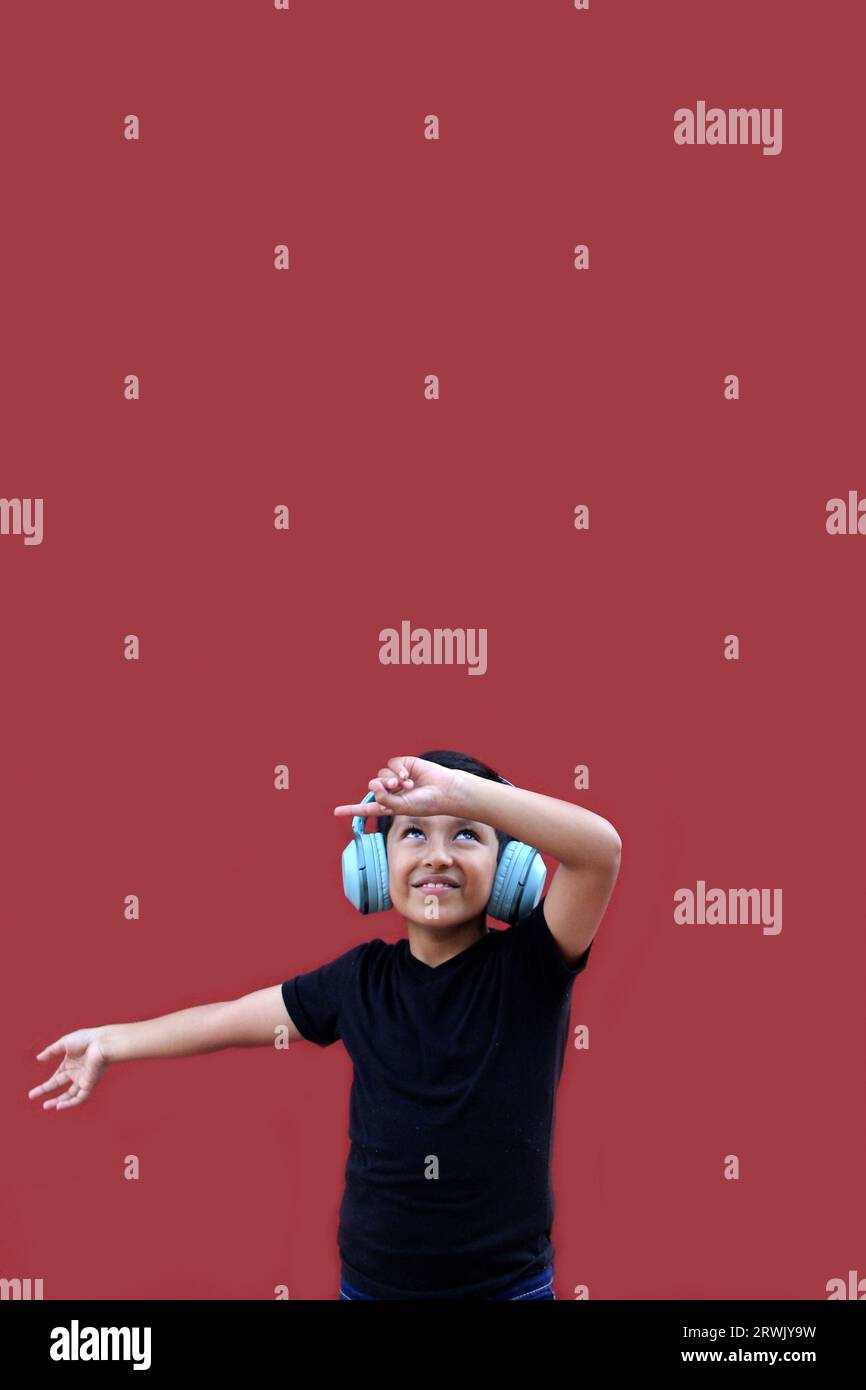 9-year-old dark-skinned Latino boy listens to his headphones and enjoys ...