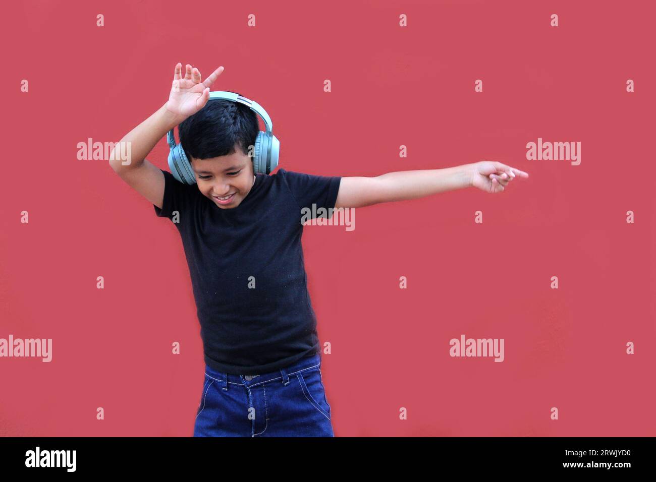 9-year-old dark-skinned Latino boy listens to his headphones and enjoys ...