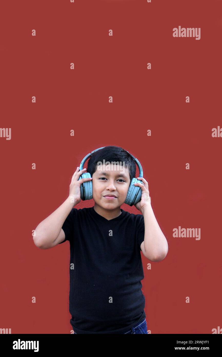 9-year-old dark-skinned Latino boy listens to his headphones and enjoys ...
