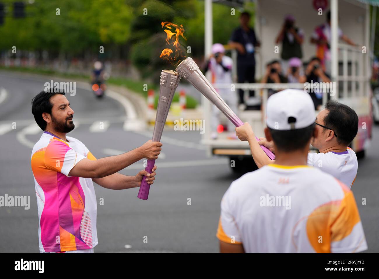 A torch bearer passes the flame during the torch relay for the 19th ...