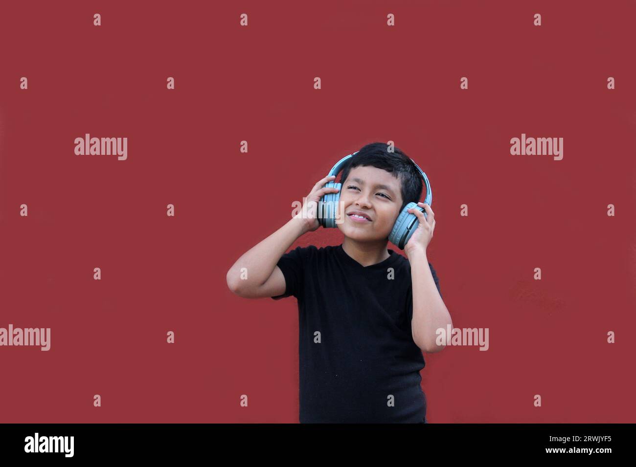9-year-old dark-skinned Latino boy listens to his headphones and enjoys ...