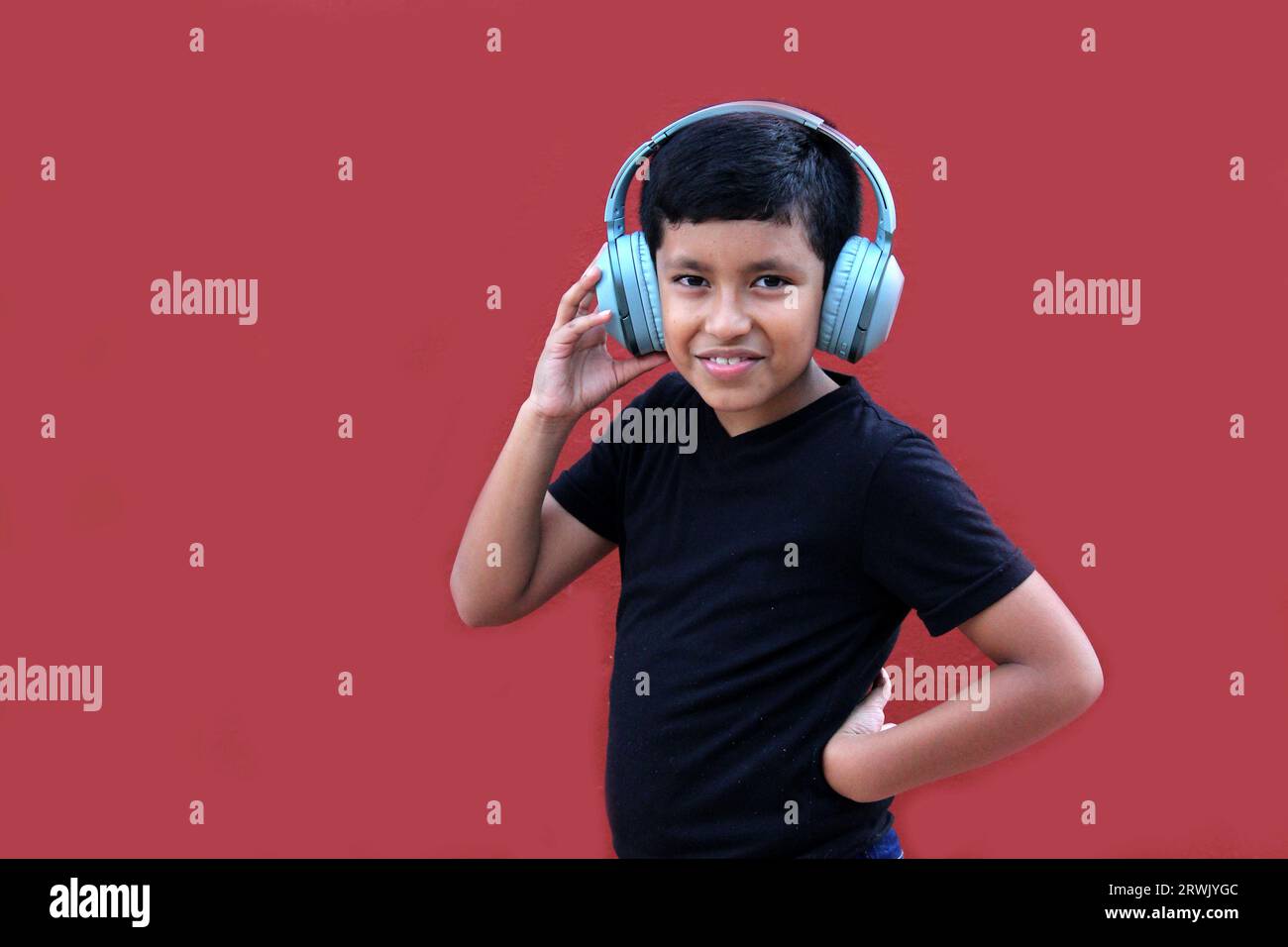9-year-old dark-skinned Latino boy listens to his headphones and enjoys ...